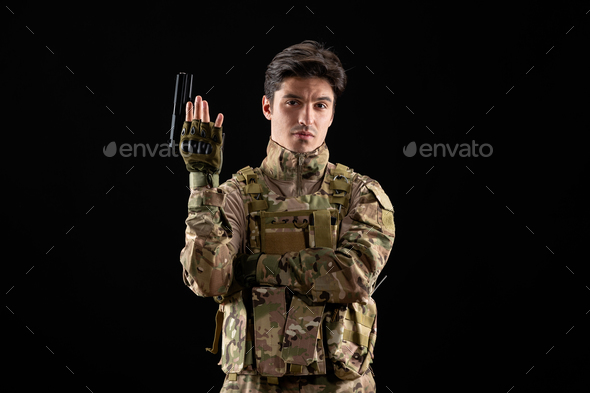 front view of military serviceman in uniform with gun black background ...