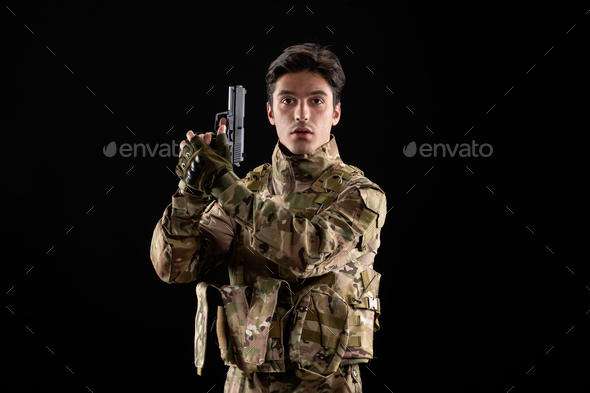 front view of military serviceman in uniform with gun on black ...