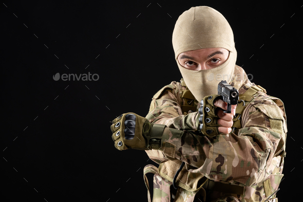 front view of young soldier in uniform with gun on black background ...