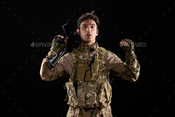 front view of young soldier in uniform with rifle on black background ...