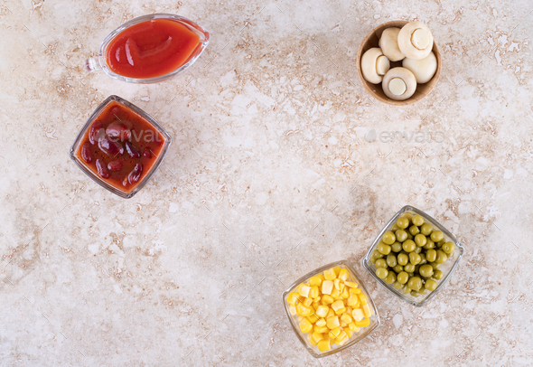 Condiments and vegetable portions in bowls on marble background Stock ...