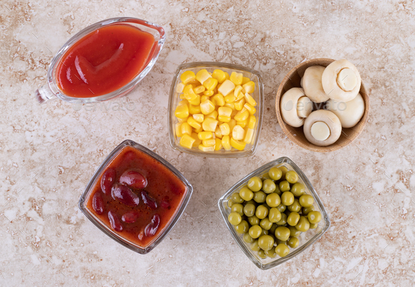 Condiments and vegetable portions in bowls on marble background Stock ...