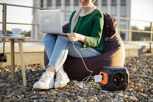Lady connecting laptop to power supply via cord outdoors Stock Photo by ...