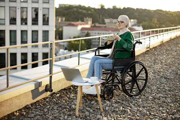 Muslim lady with disability eating food on roof terrace Stock Photo by ...