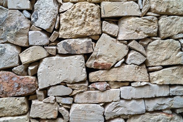 Texture of a wall made of rocks of different sizes Stock Photo by wirestock