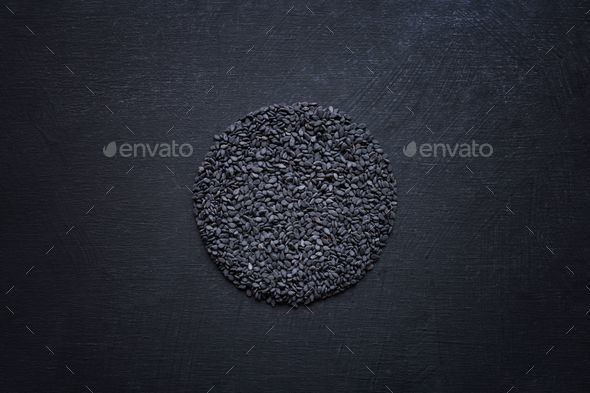 Top view of black sesame seeds shaped as a circle on a black background ...