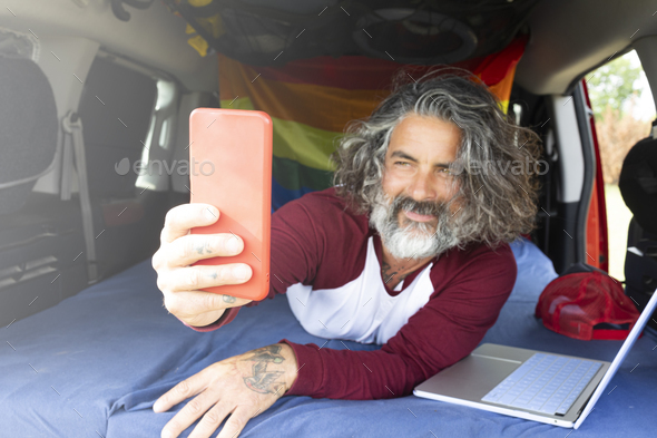 Happy travel blogger making a selfie on smartphone, inside minivan ...