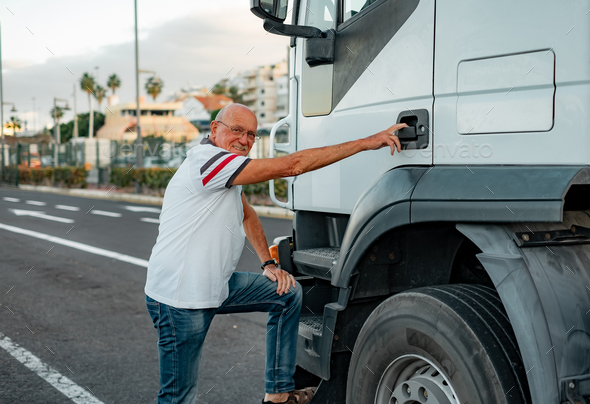 Senior truck driver prepares to climb into the cab of his truck ...