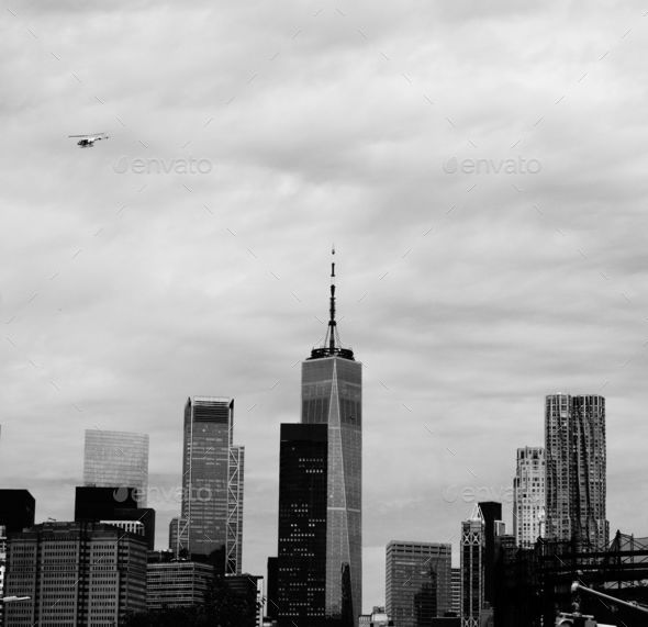 Grayscale of a helicopter flying over downtown New York under a cloudy ...