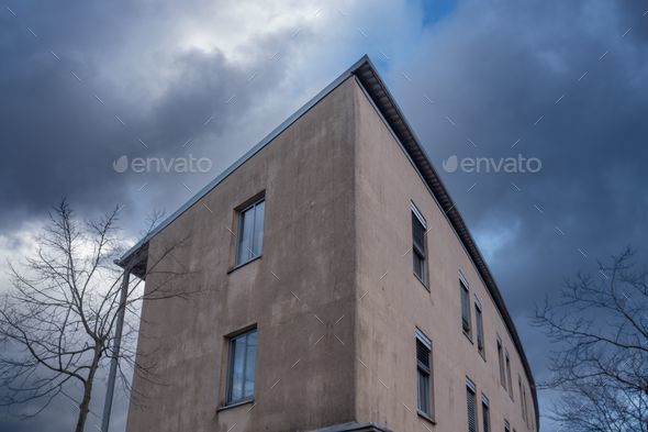 Front view of a large building, surrounded by trees and dark, menacing ...