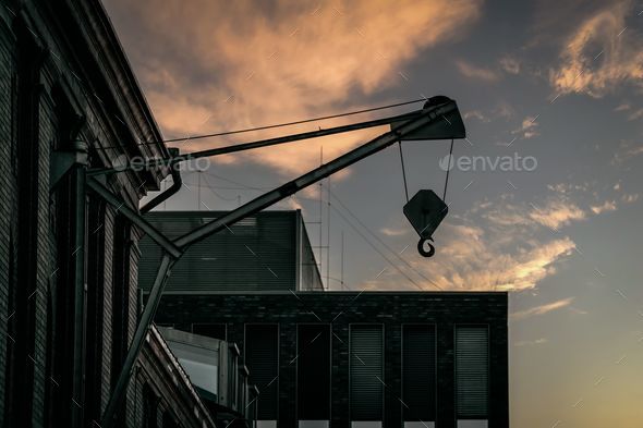 Picture of a crane attached to a modern building at dusk Stock Photo by ...