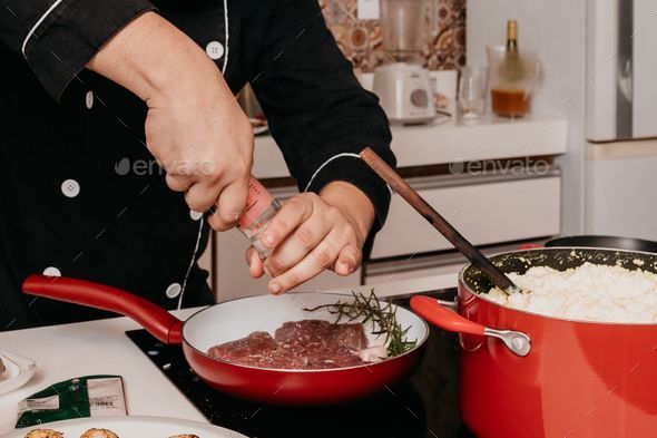 chef using ladle to cook steak in a red pan Stock Photo by wirestock