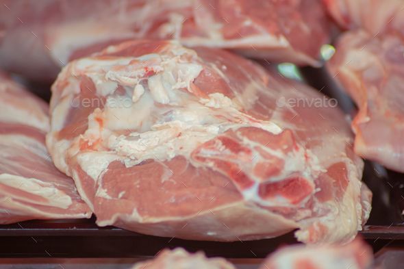Raw cuts of meat, laid out on a black surface Stock Photo by wirestock