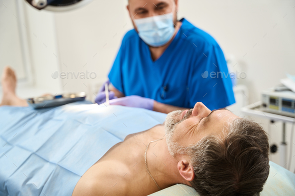 Patient lying on operating table is given injection during surgery ...