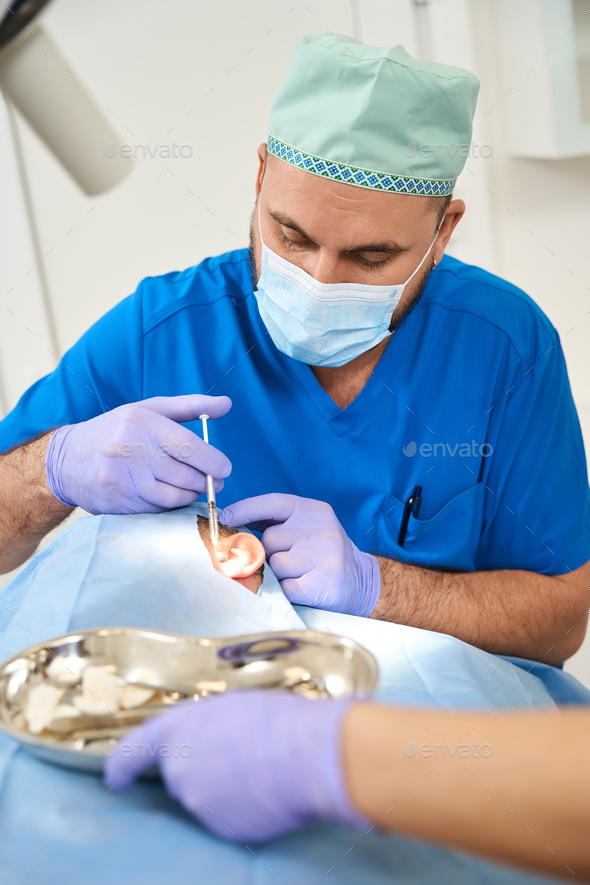Doctor in operating room who makes injection into man ear Stock Photo ...