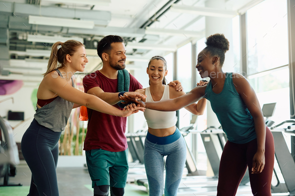 Multiracial group of athletes holding hands in unity after successful ...