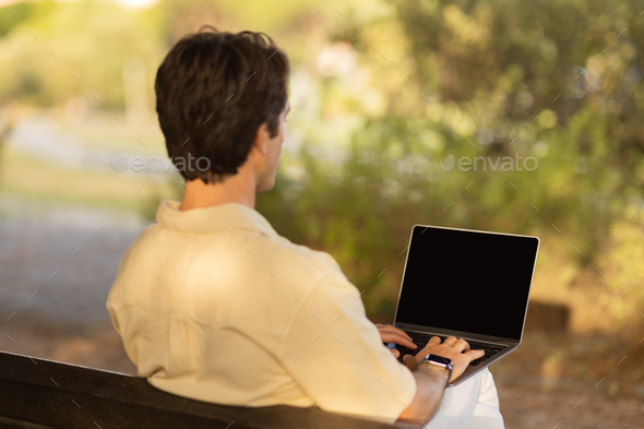 Back view man sitting on bench in park, using laptop Stock Photo by ...