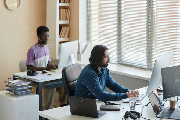 Young serious man pressing keys of computer keyboard by workplace Stock ...