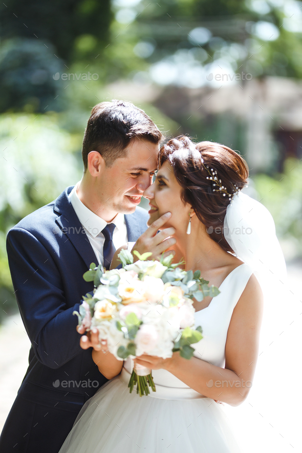 Bride and groom walk together in the park. Pretty bride and stylish ...
