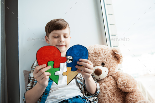 Smiling boy holds a heart as a sign of solidarity with people suffering ...