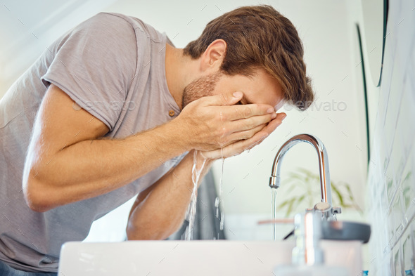 One handsome man washing his face in a bathroom at home. Caucasian male ...