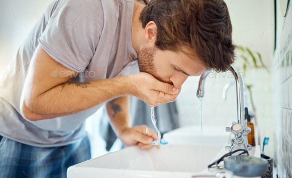 One handsome man rinsing his mouth in a bathroom at home. Caucasian ...