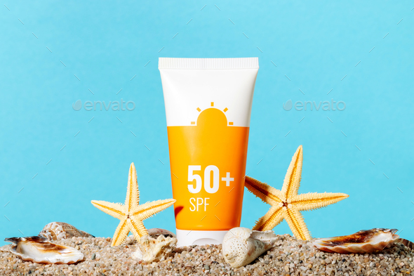 Sunscreen in an orange tube on blue background with beach sand. Summer ...