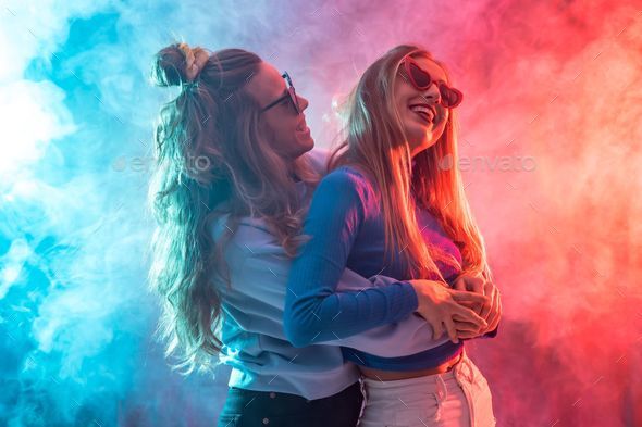 Females embracing in a warm hug illuminated by bright neon lights ...