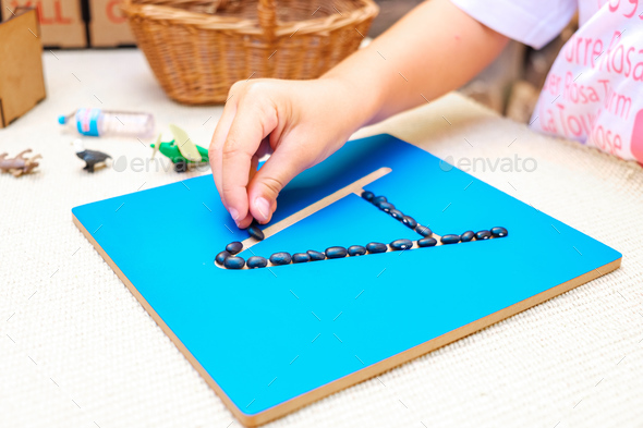 A girl tracing the outline of a letter, using the montessori ...