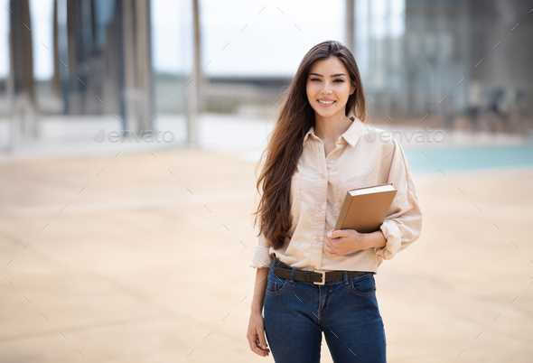 Cheerful hispanic student lady posing with books standing outdoor Stock ...