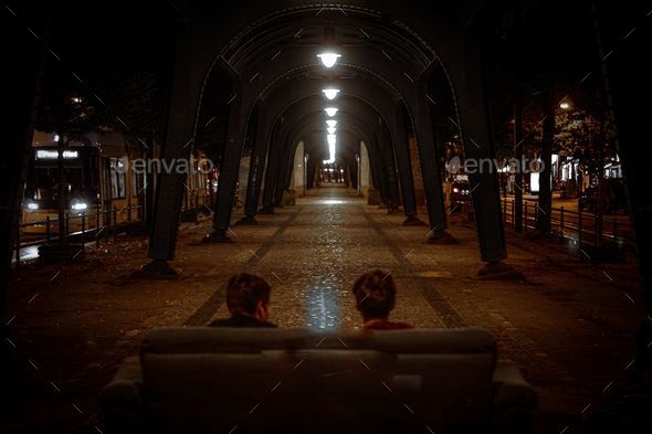 Two people sitting on a bench in an underground tunnel at night. Stock ...