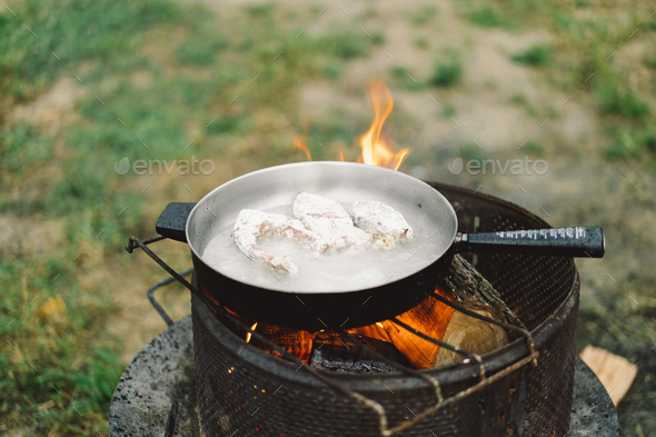 Man cooking fish on fire in nature, camping outdoors Stock Photo by ...