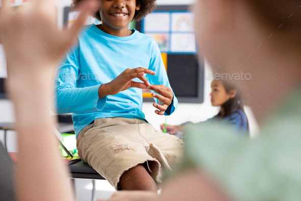 Happy diverse schoolchildren using sign language in school classroom ...