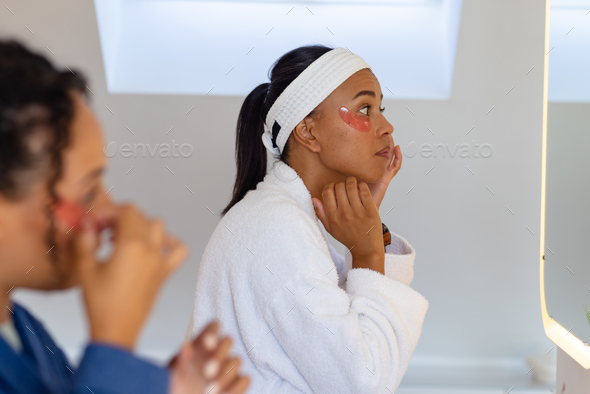 Happy Biracial Lesbian Couple In Bathrobes Wearing Eye Masks In