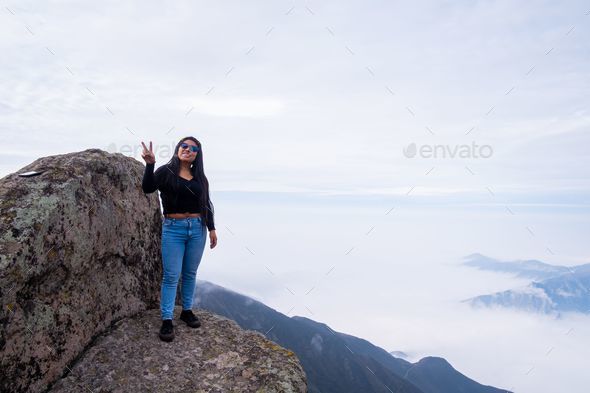 Young Hispanic woman stands on the edge and poses for the camera. Peru ...