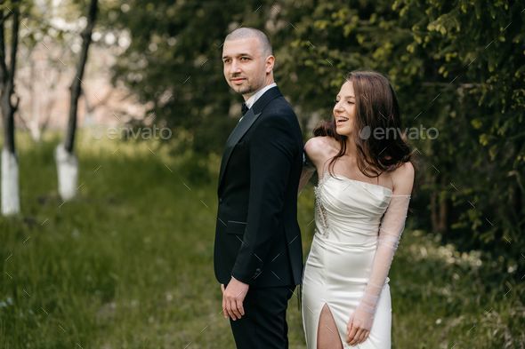 Bride and groom posing together in a green garden on their wedding day ...