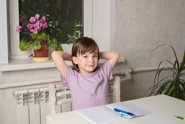 Relaxed smiling girl sits at the table, leans back in her chair Stock ...