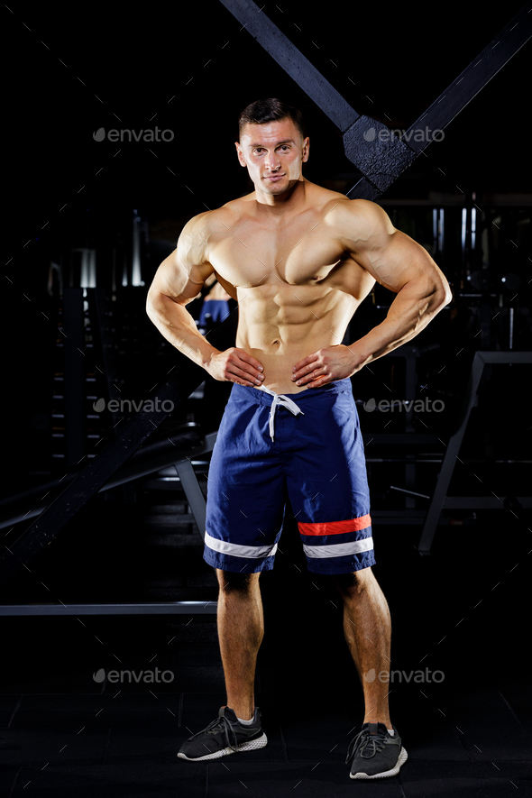 Young bodybuilder with great muscles posing in gym Stock Photo by skumer