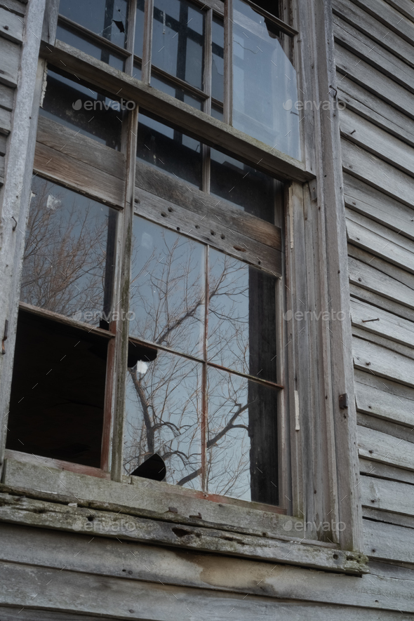 Broken window of an abandoned antique wooden house Stock Photo by wirestock