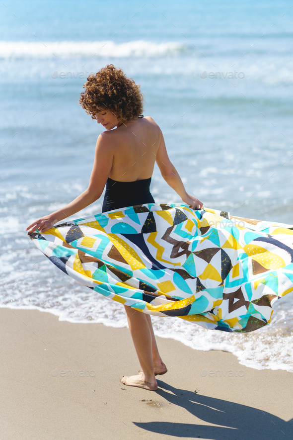 Back view of stylish woman on sandy beach Stock Photo by javi_indy