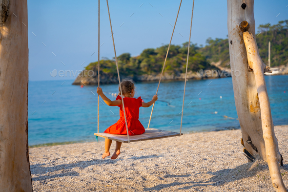 Little girl on wooden swing on Oludeniz beach. Summer holiday in ...