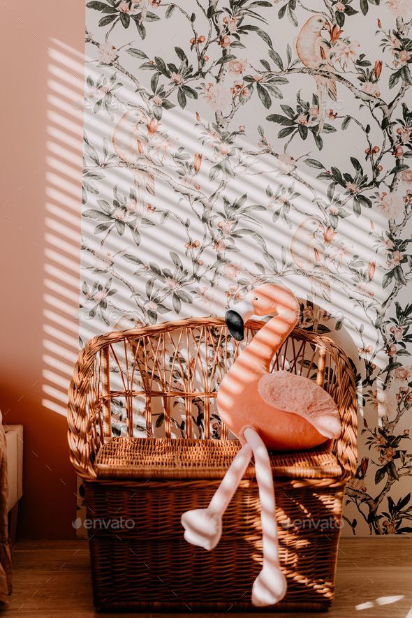 Pink flamingo perched atop a wicker bed in a room with a patterned ...