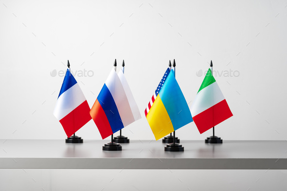 Small country flags standing at a table Stock Photo by FabrikaPhoto