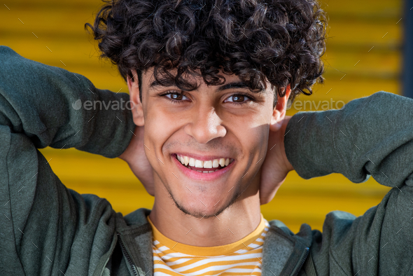Close up happy young North African man laughing with hands behind head ...