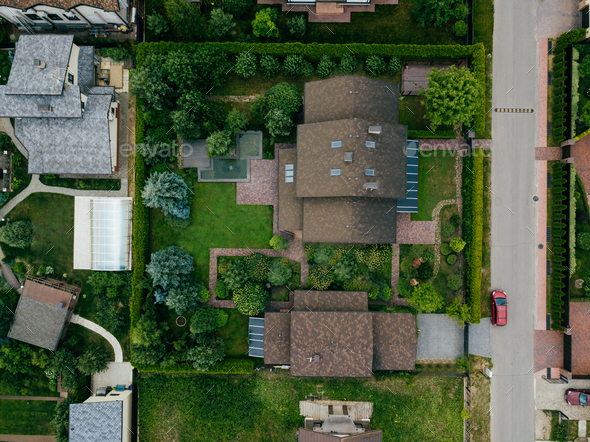 Aerial top view of house shingle roof and car on paved yard with green ...
