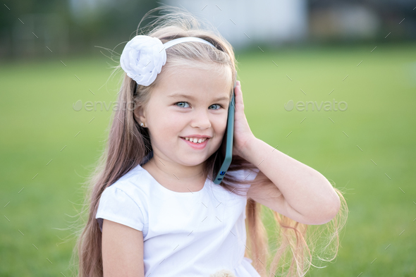 Pretty little child girl talking on mobile phone smiling happily ...