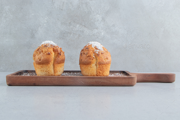 Cupcakes with vanilla powder toppings on a tray on marble background ...