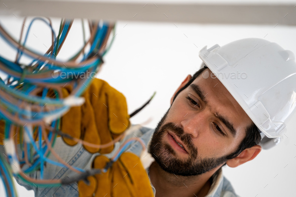 Electrician mounting wiring for electric sockets on the construction ...
