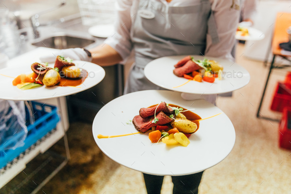 Waitress serving plates with roast beef and potatoes in restaurant ...