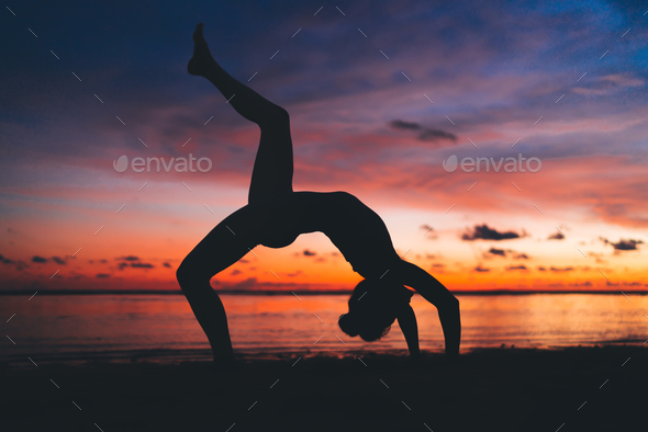 Woman in Inverted Staff Pose on beach at sunset Stock Photo by GaudiLab